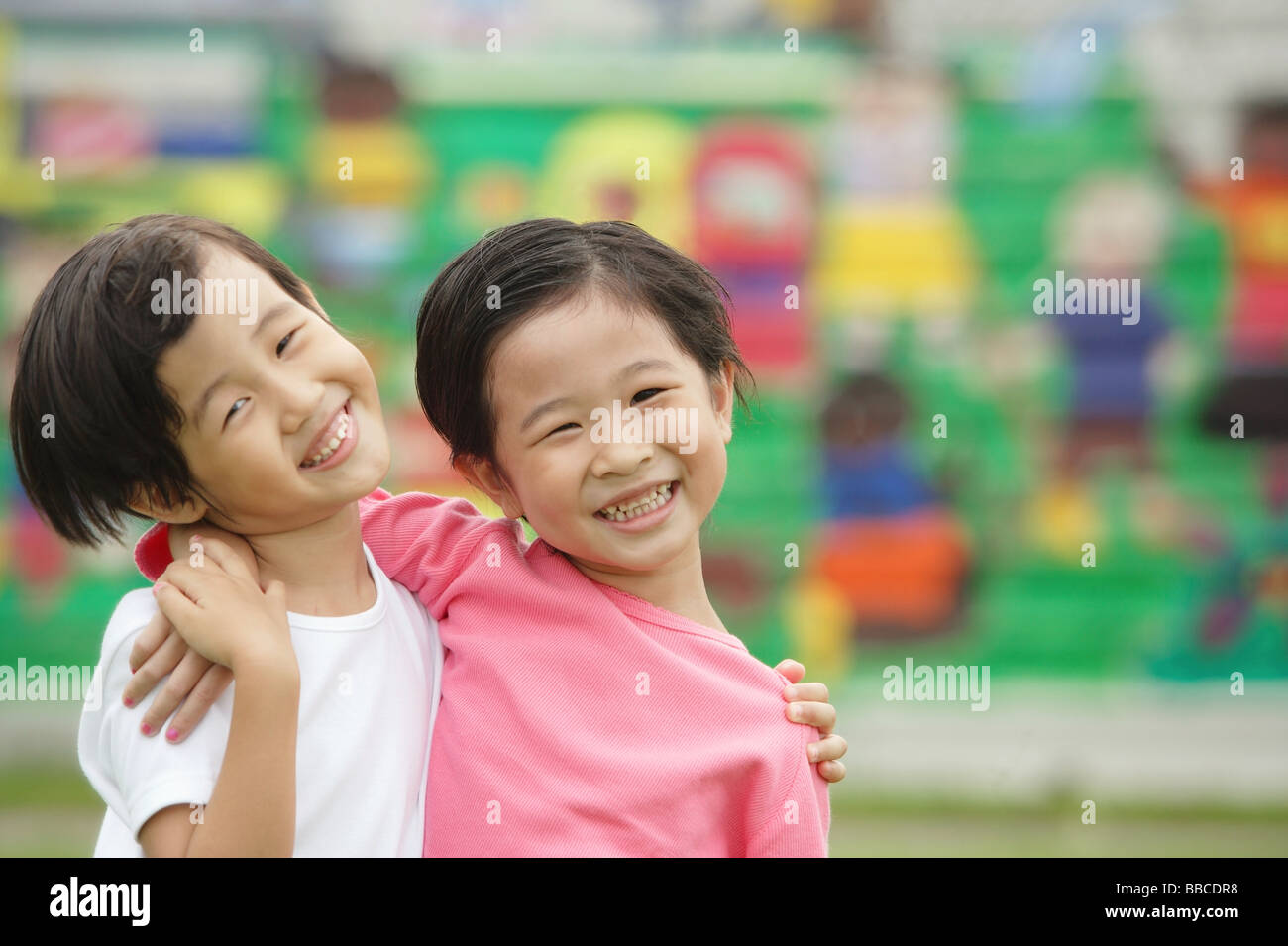 Two girls with arms around each other, smiling at camera Stock Photo ...