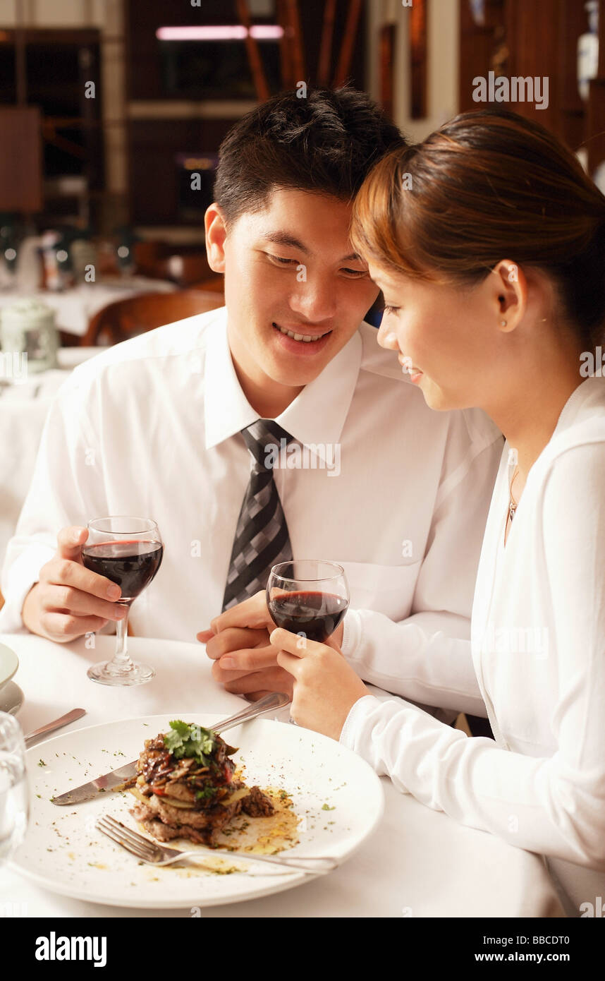 Couple in restaurant, sitting side by side, holding hands Stock Photo ...
