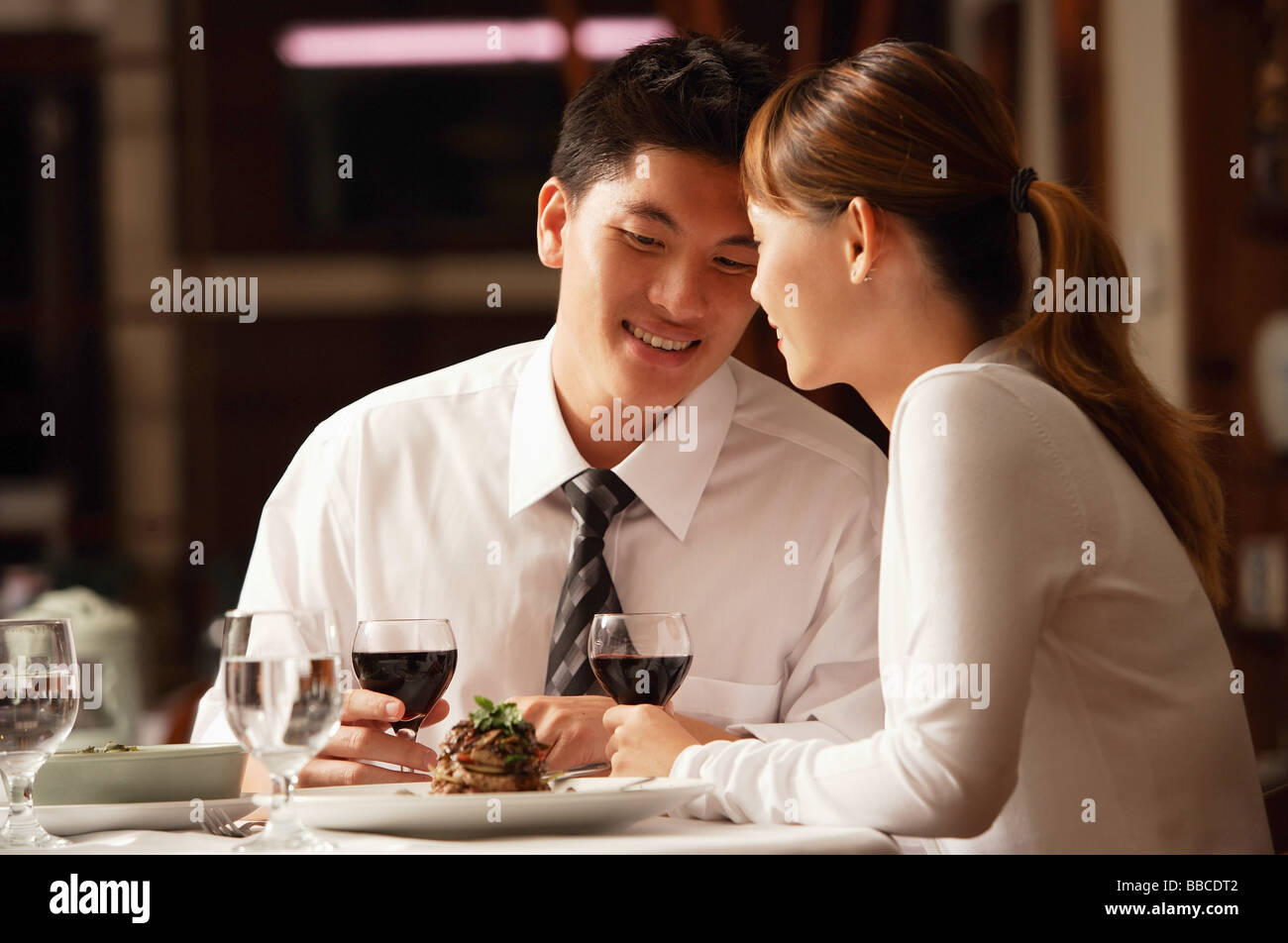 Couple in restaurant, sitting side by side Stock Photo - Alamy