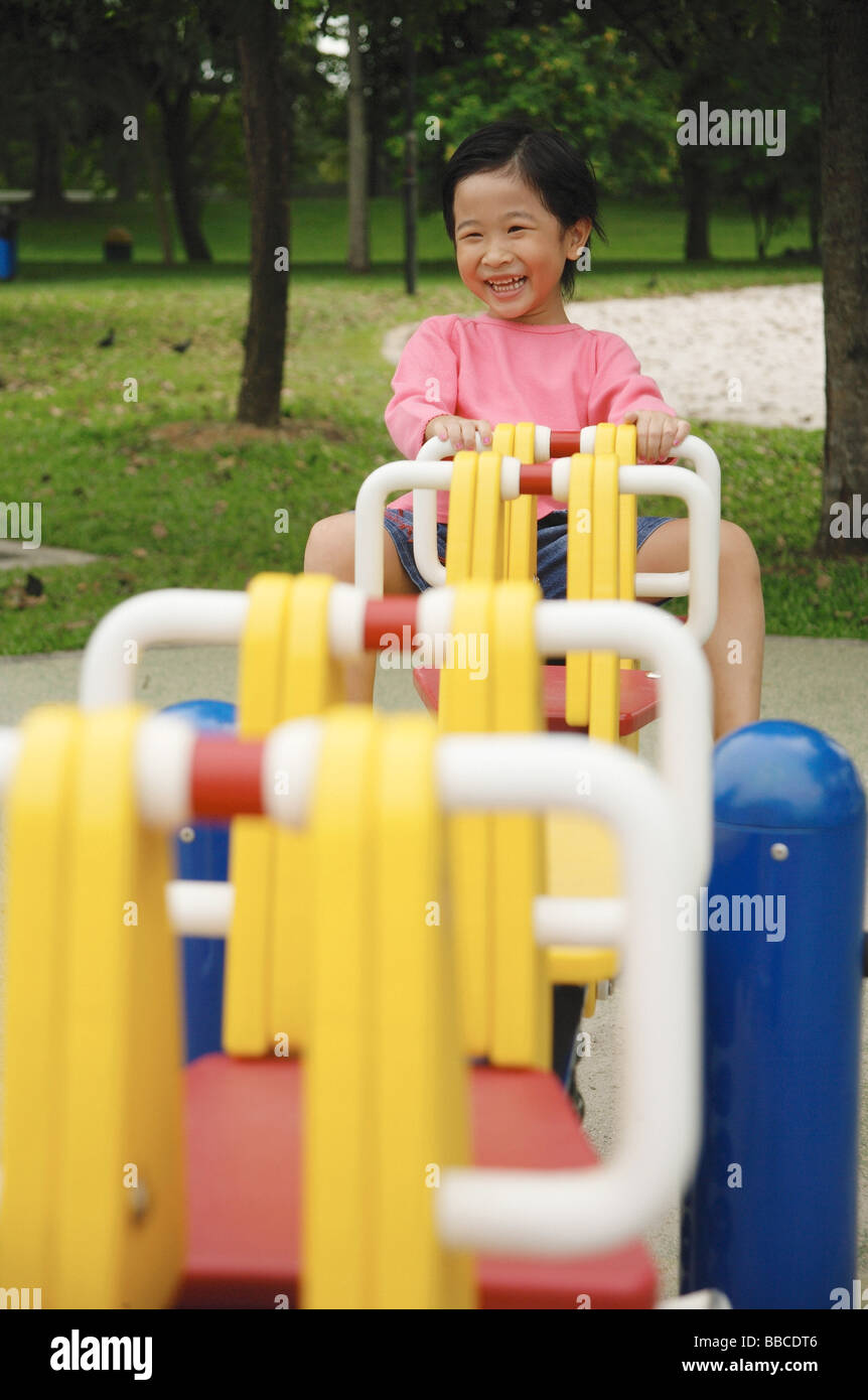 Young girl sitting on seesaw, smiling at camera Stock Photo - Alamy