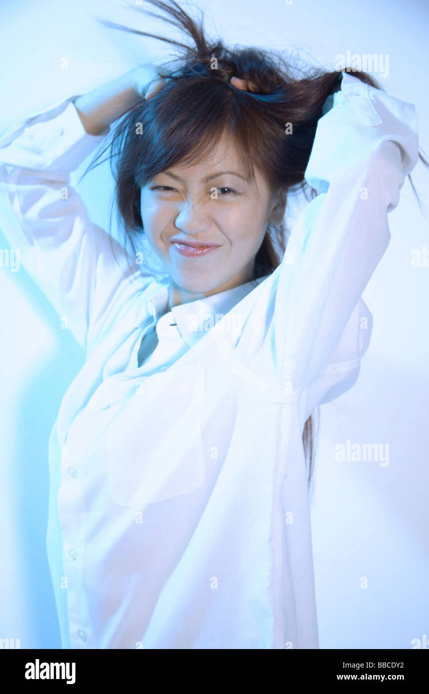 Young woman, hands in hair, grimacing at camera Stock Photo - Alamy
