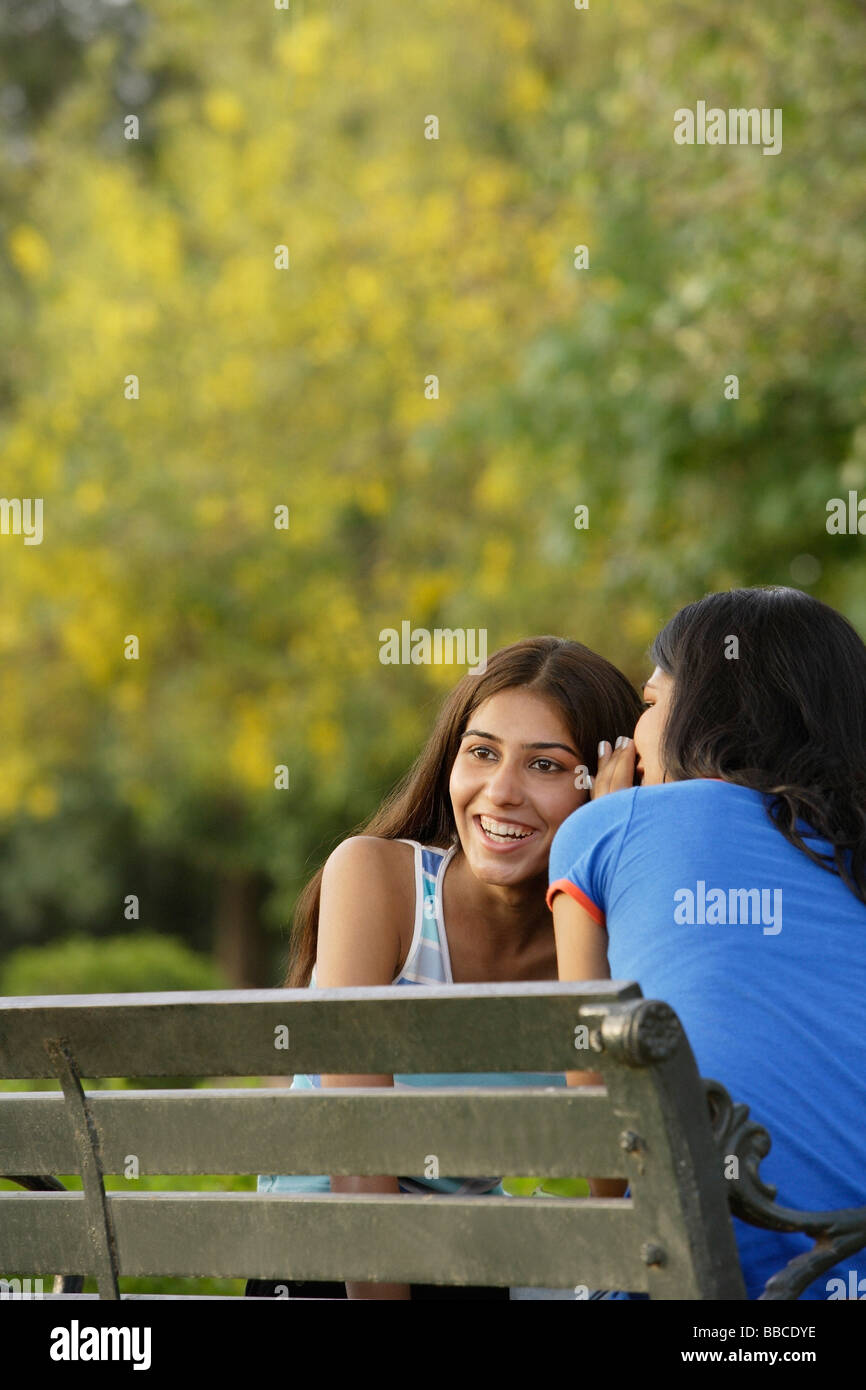 Two teen girls telling secrets in park Stock Photo - Alamy