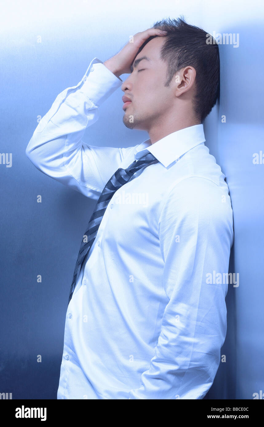 Man in shirt and tie, leaning on wall, hand on head Stock Photo - Alamy