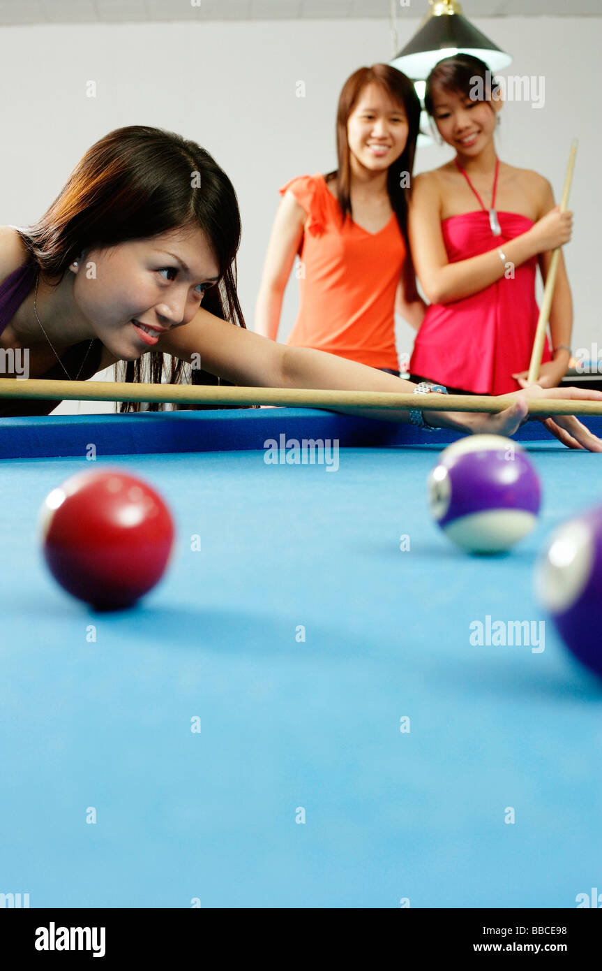 Woman holding pool cue, aiming, women watching in the background Stock ...