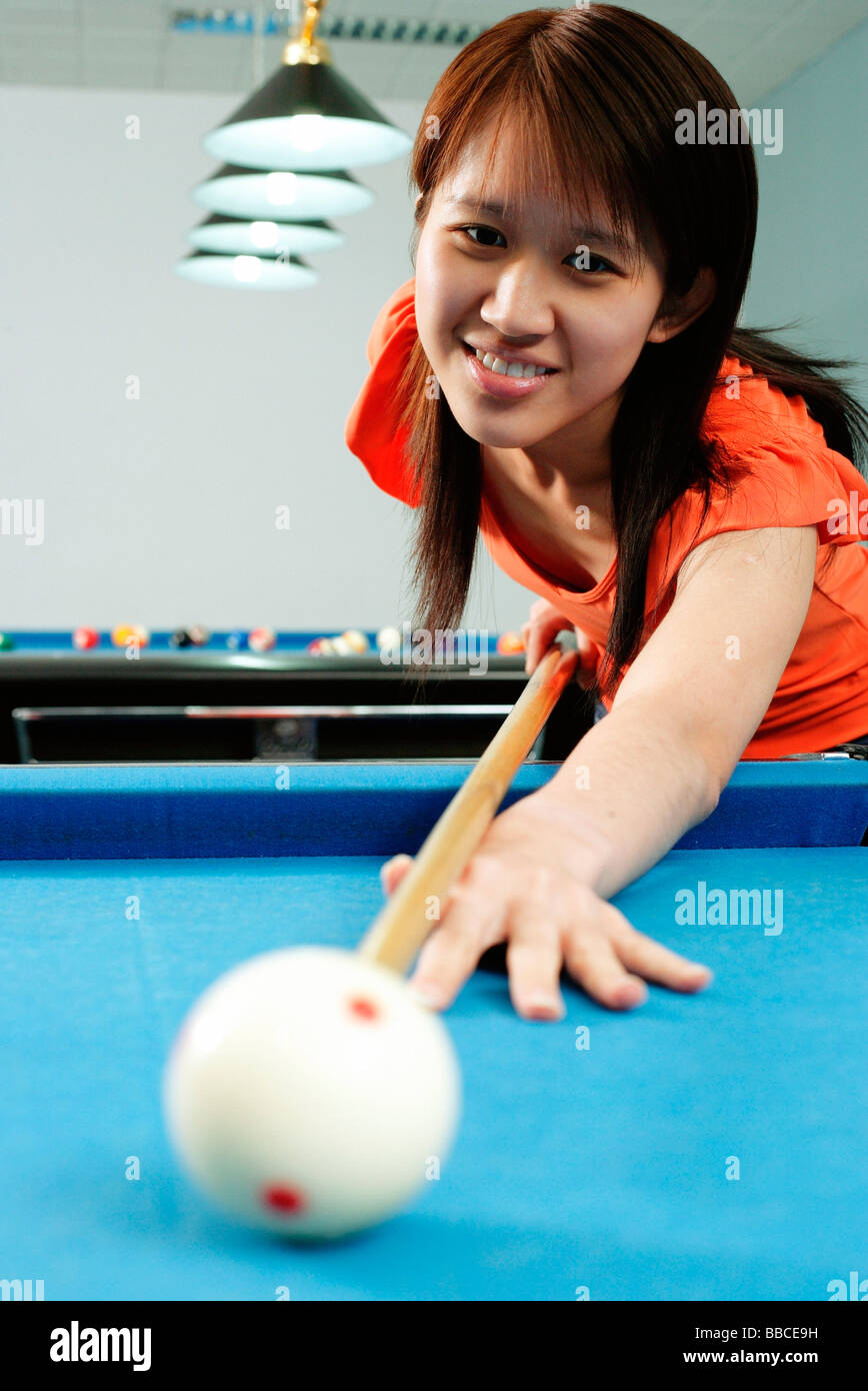 Woman in orange top, holding pool cue, aiming at ball Stock Photo - Alamy