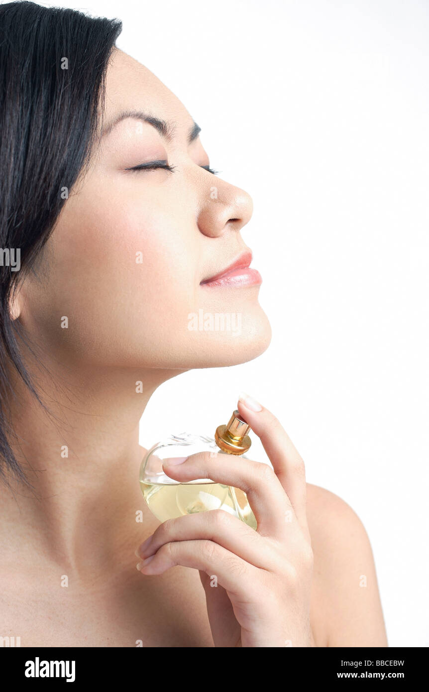 Woman applying perfume, sideview Stock Photo - Alamy