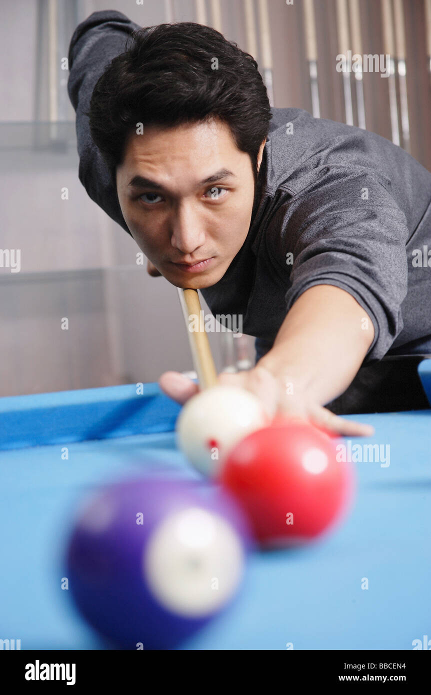 Man holding pool cue, aiming at ball Stock Photo - Alamy