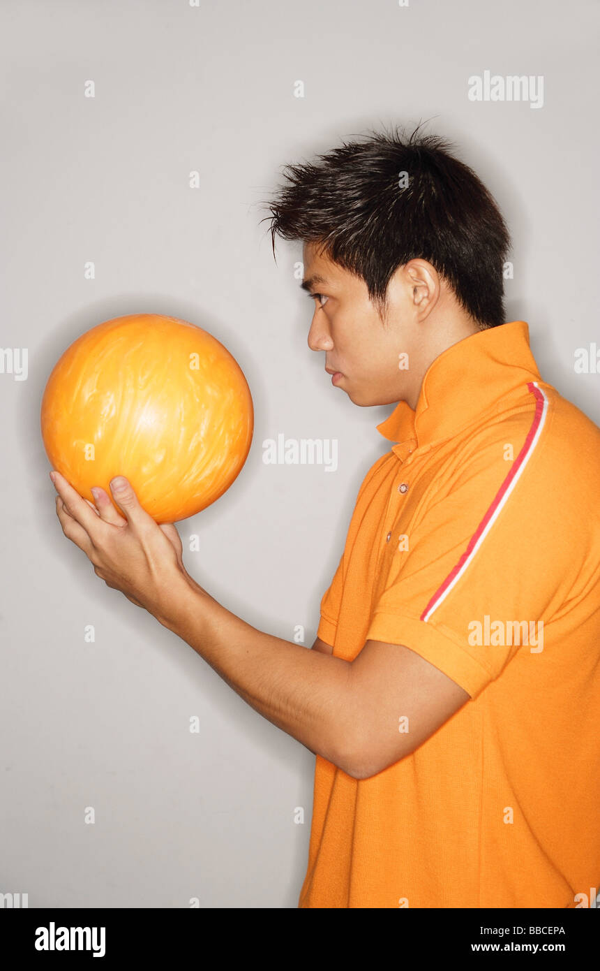 Man looking at bowling ball, side view Stock Photo - Alamy