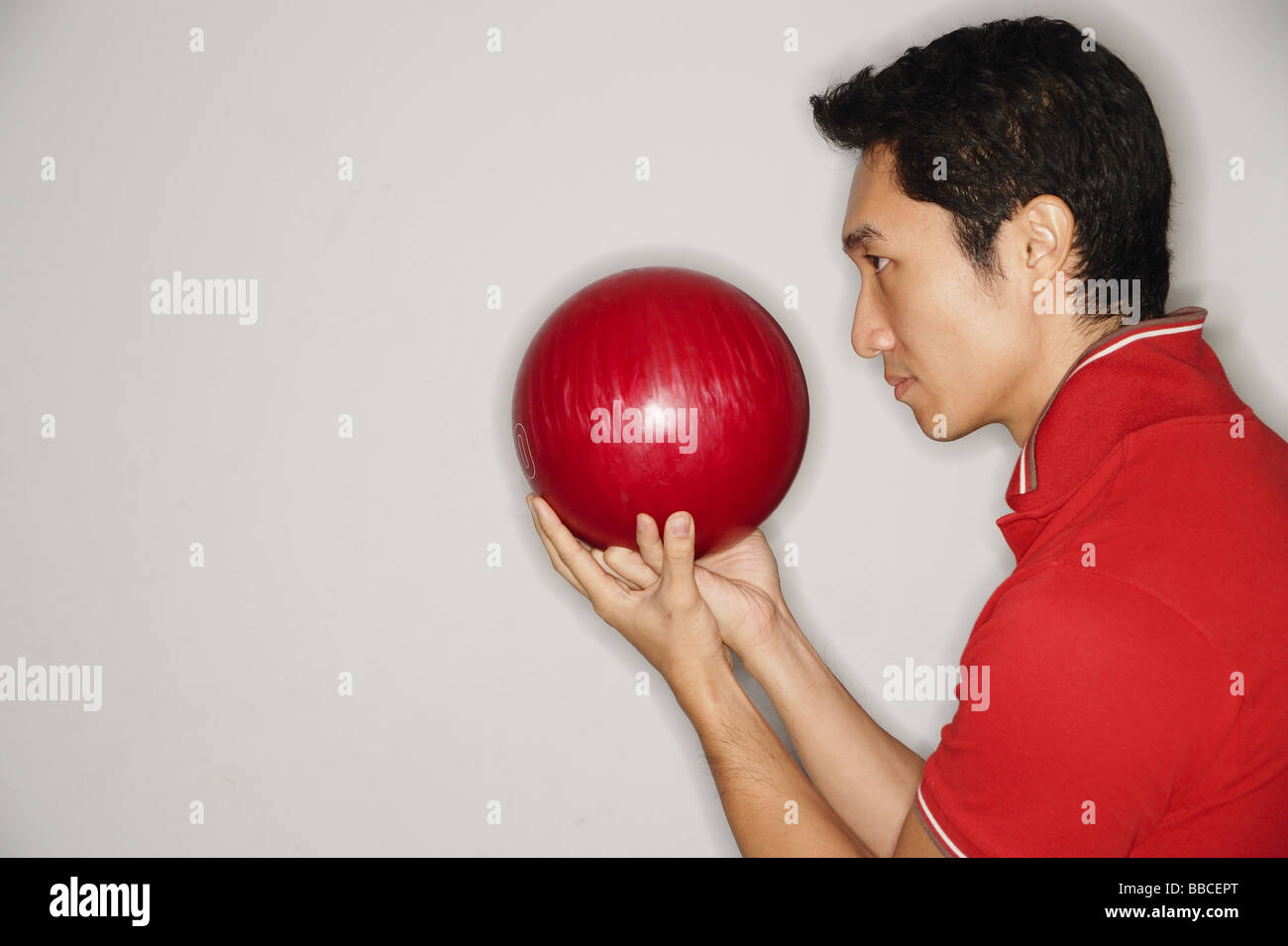 Man holding bowling ball in front of face, side view Stock Photo - Alamy