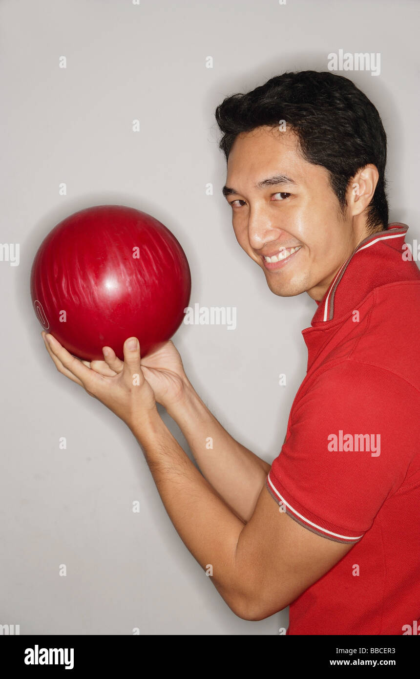 Man holding bowling ball, turning to smile at camera Stock Photo - Alamy