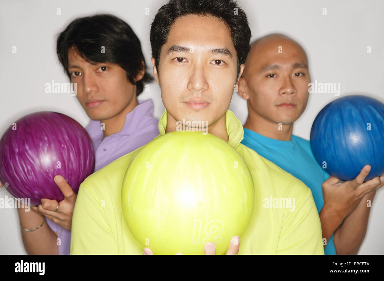 Three men holding bowling balls, looking at camera Stock Photo - Alamy