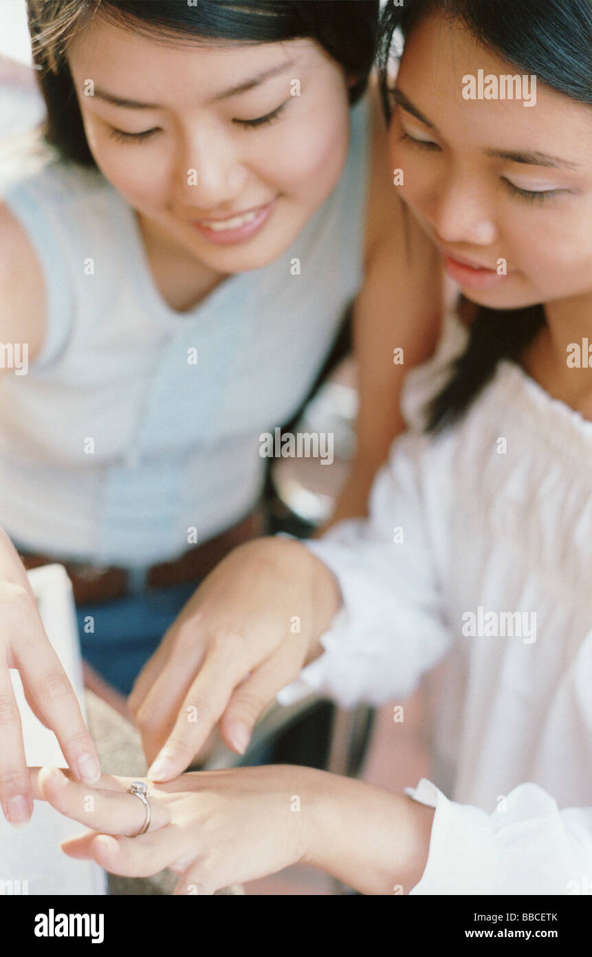 Young women looking at ring on finger, smiling Stock Photo - Alamy