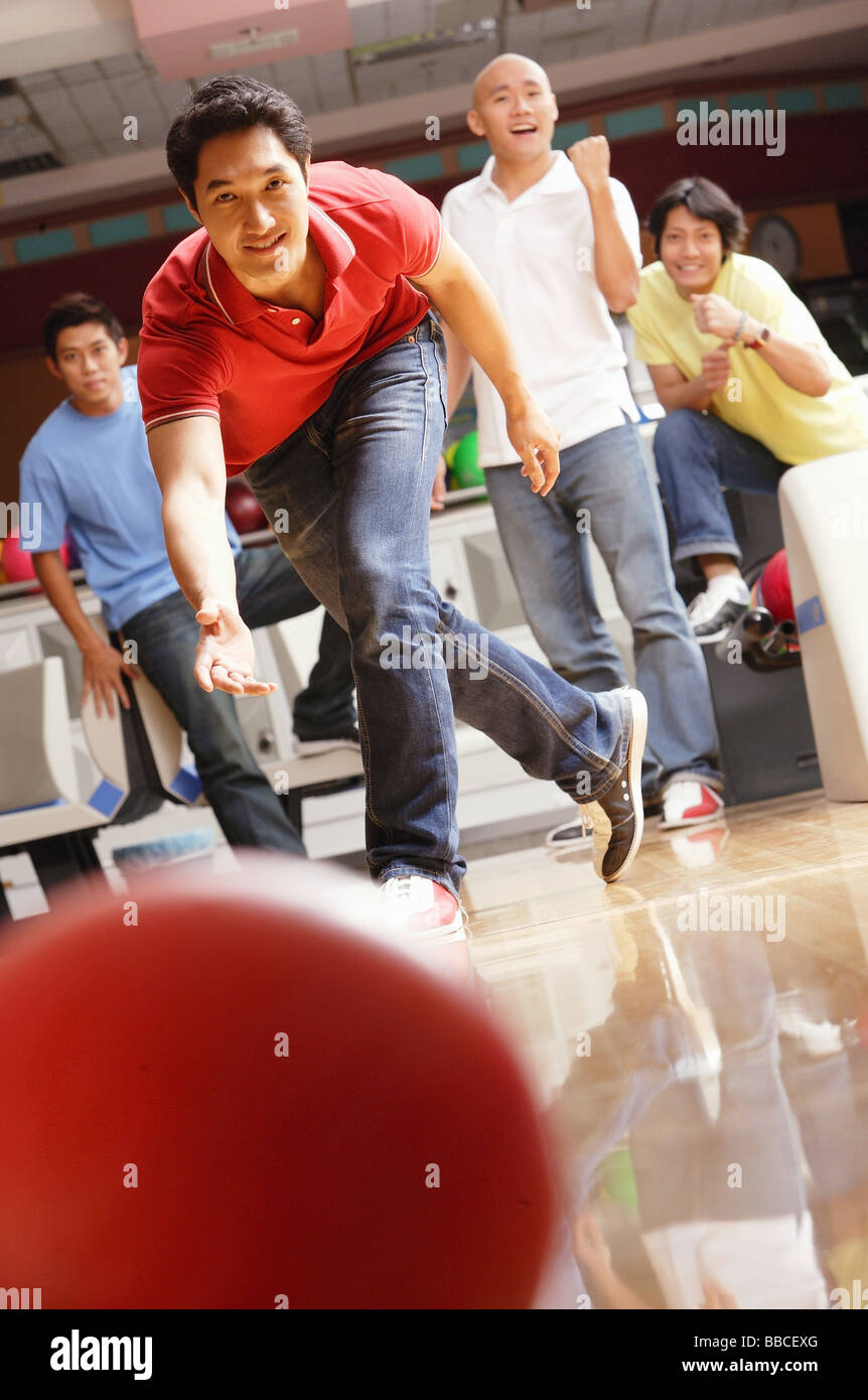 Man bowling, friends in the background, cheering Stock Photo - Alamy