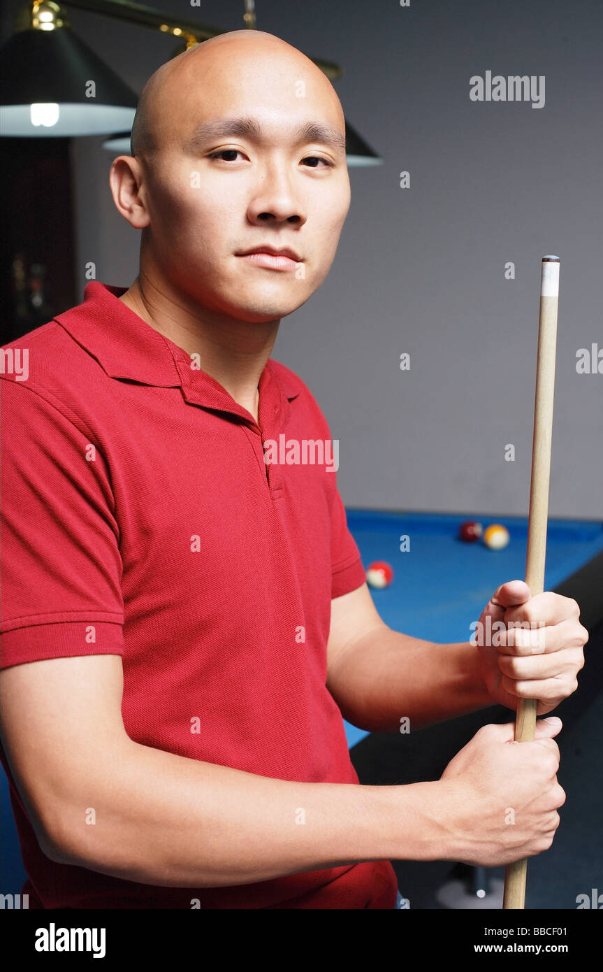 Man holding pool cue, looking at camera Stock Photo - Alamy