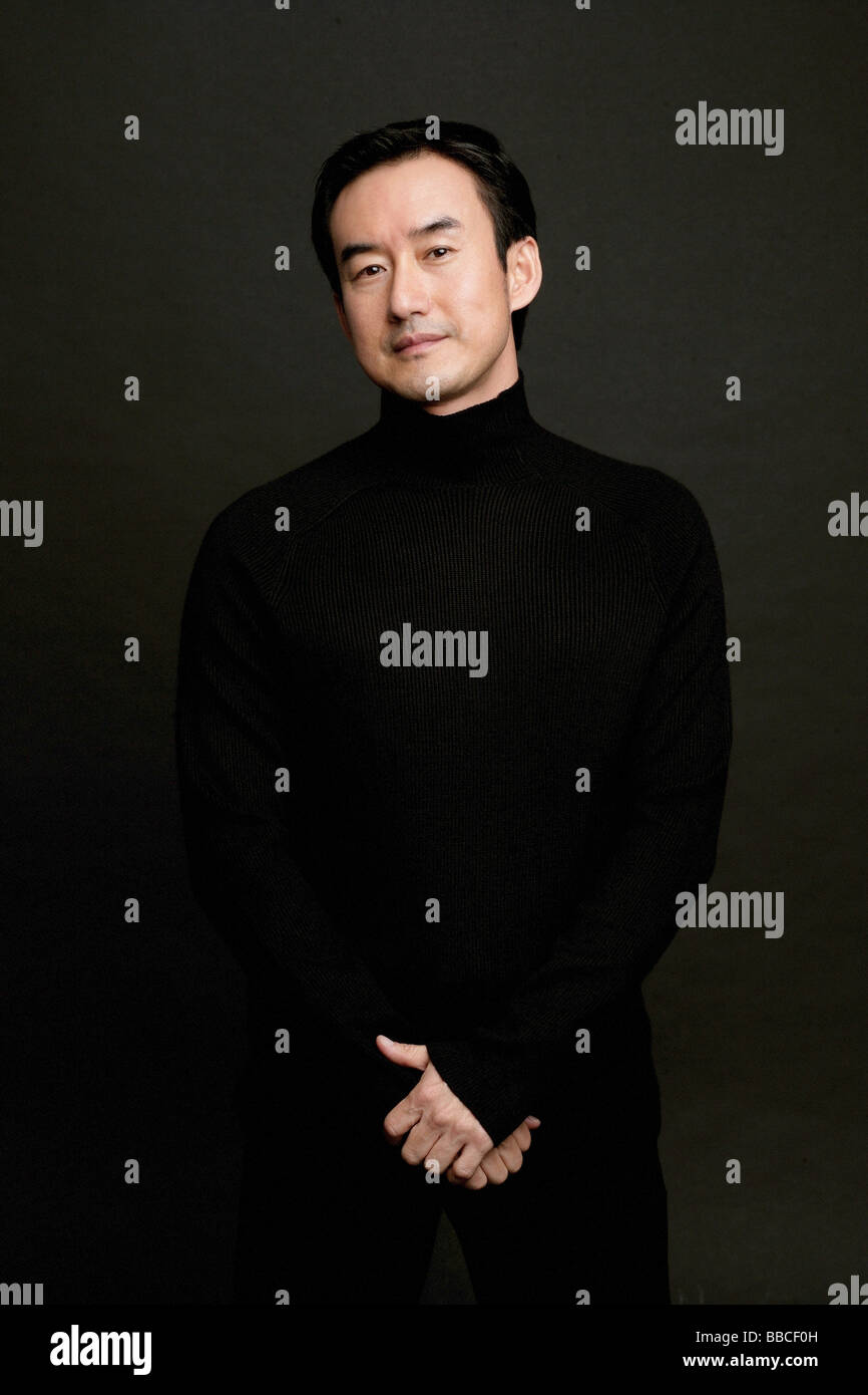 Man standing, looking at camera, black background Stock Photo - Alamy