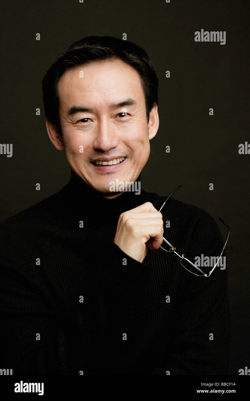 Man holding glasses, smiling, black background Stock Photo - Alamy
