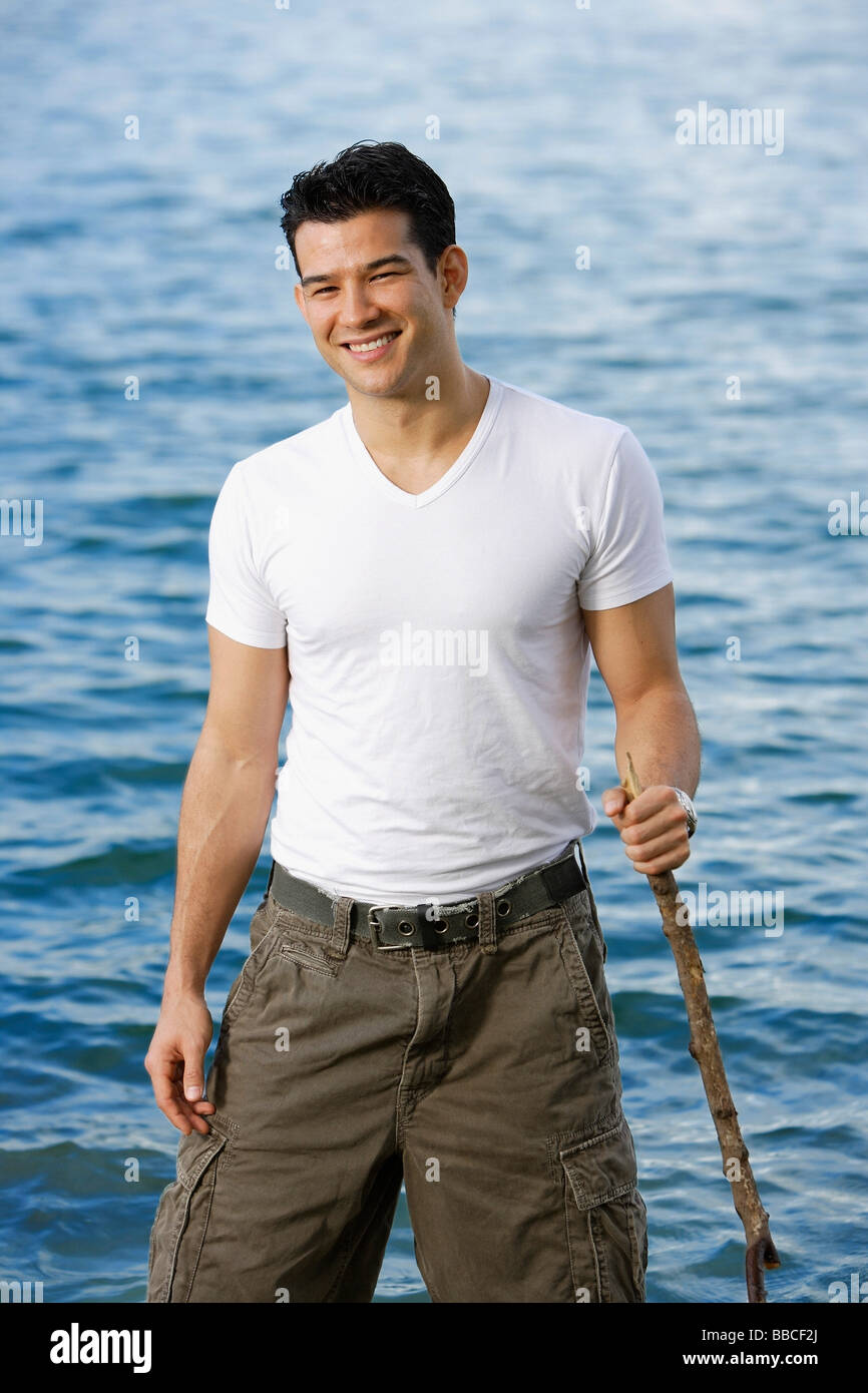 Man standing in lake, holding stick Stock Photo - Alamy