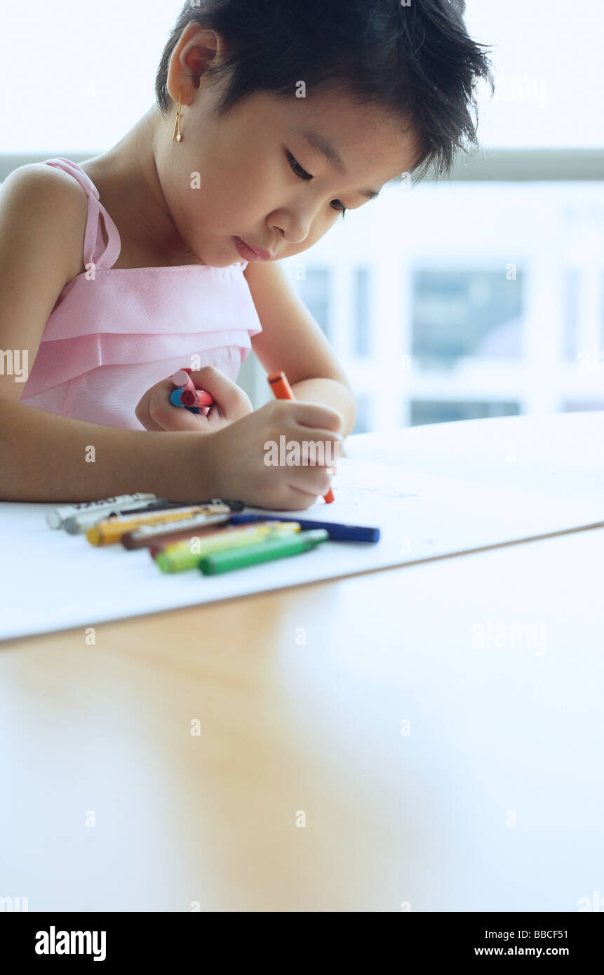 Young girl looking down, drawing with crayons Stock Photo - Alamy