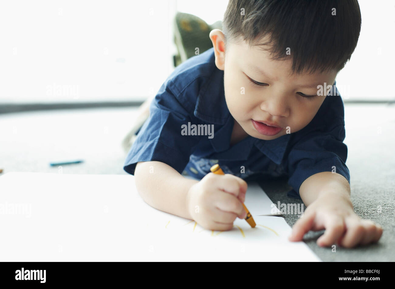 Young boy lying on floor, drawing with crayon Stock Photo - Alamy