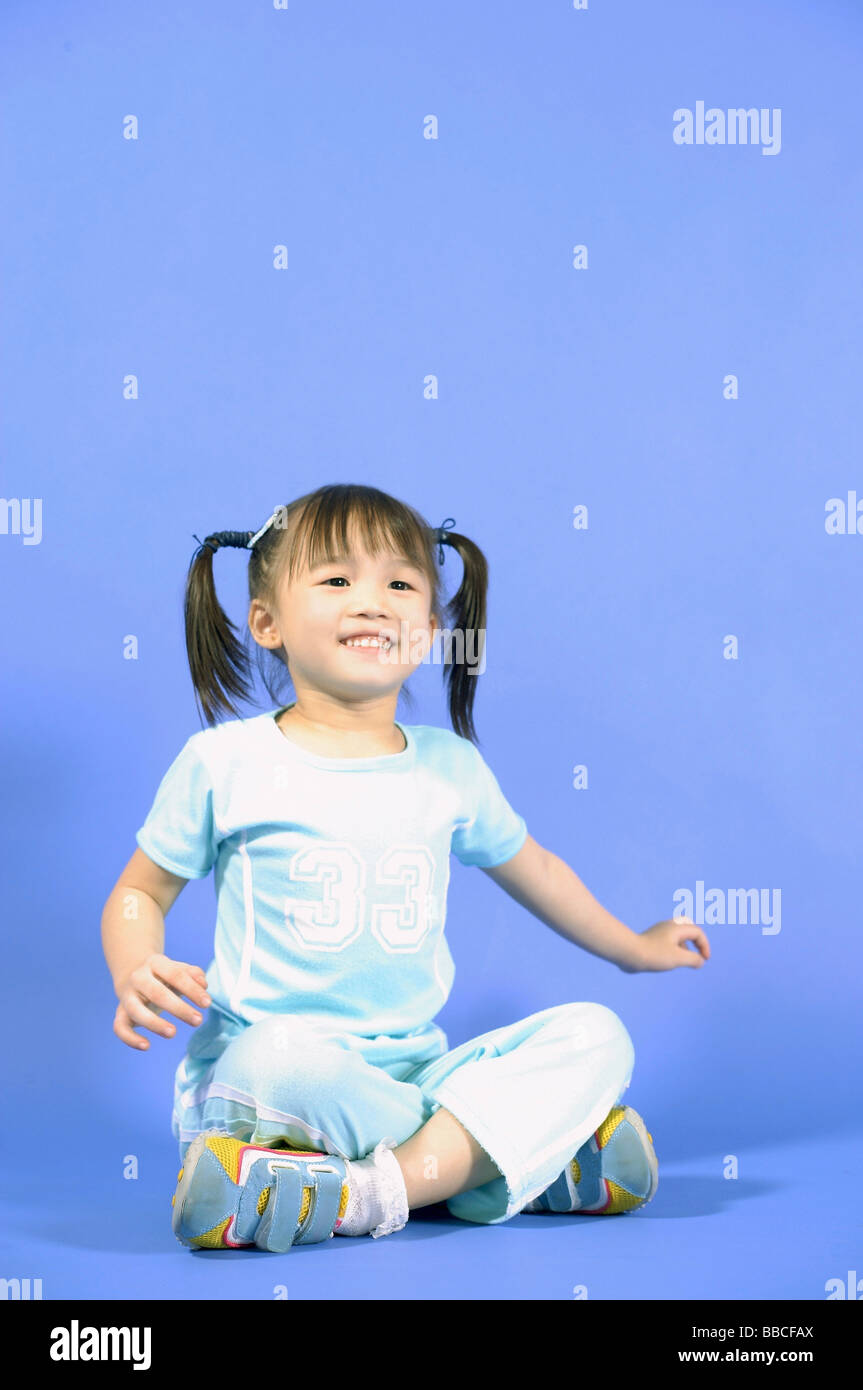 Girl sitting cross-legged, smiling Stock Photo - Alamy
