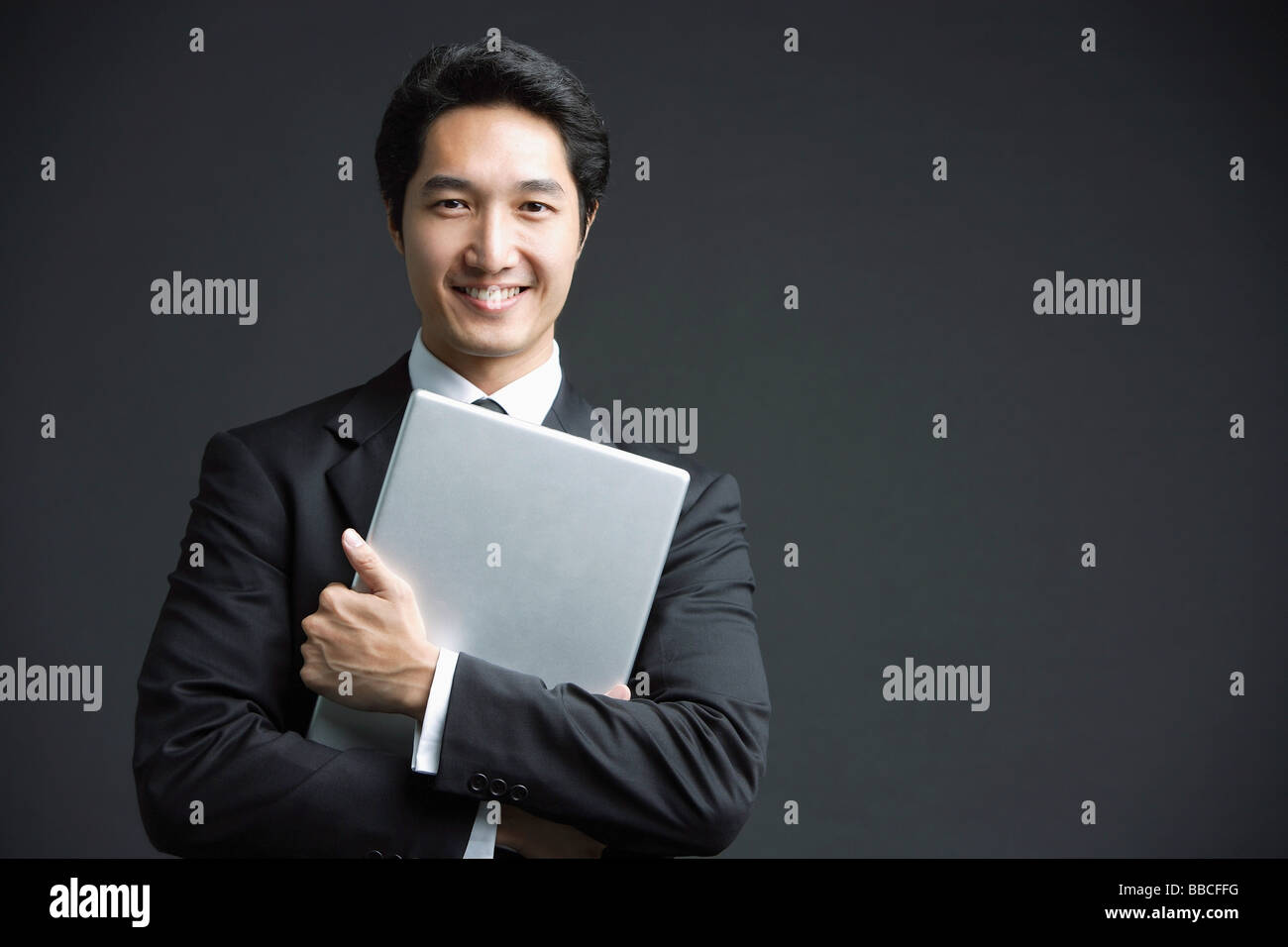 Businessman hugging laptop, looking at camera, smiling Stock Photo - Alamy
