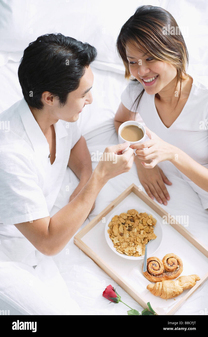 Smiling couple having breakfast on bed at home couple hi-res stock ...