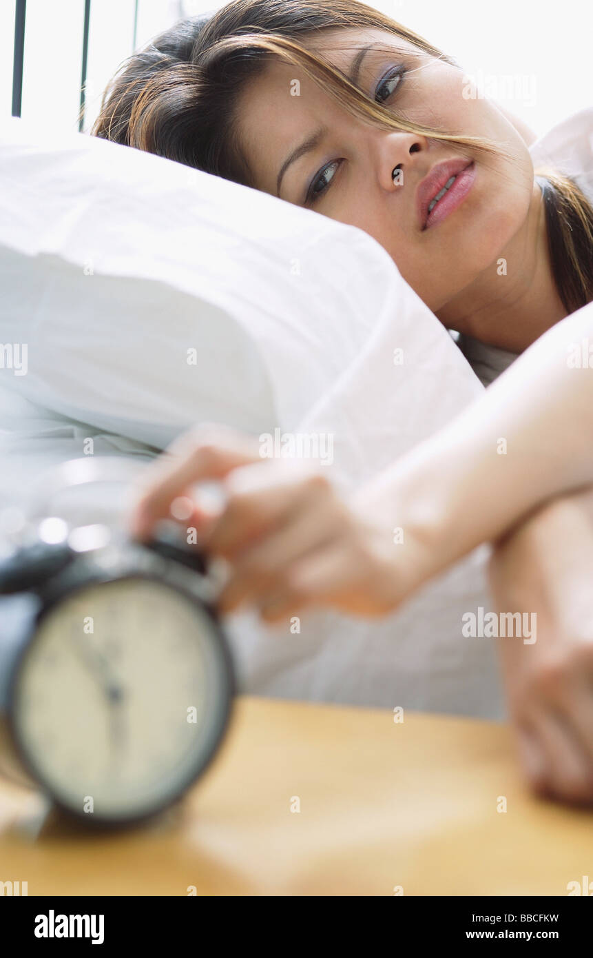 Woman reaching to switch off alarm clock Stock Photo - Alamy