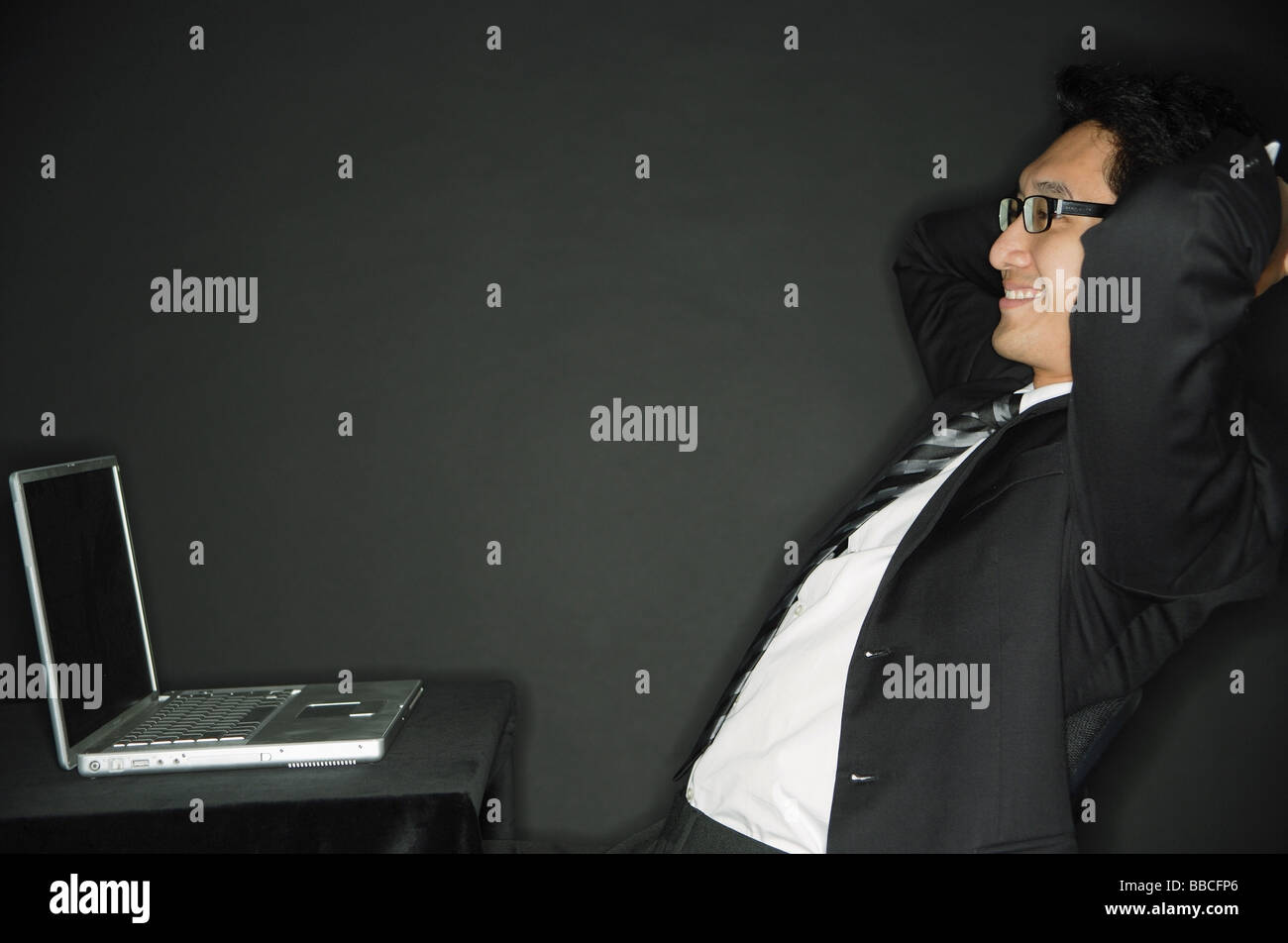 Businessman leaning back, facing laptop, smiling Stock Photo - Alamy