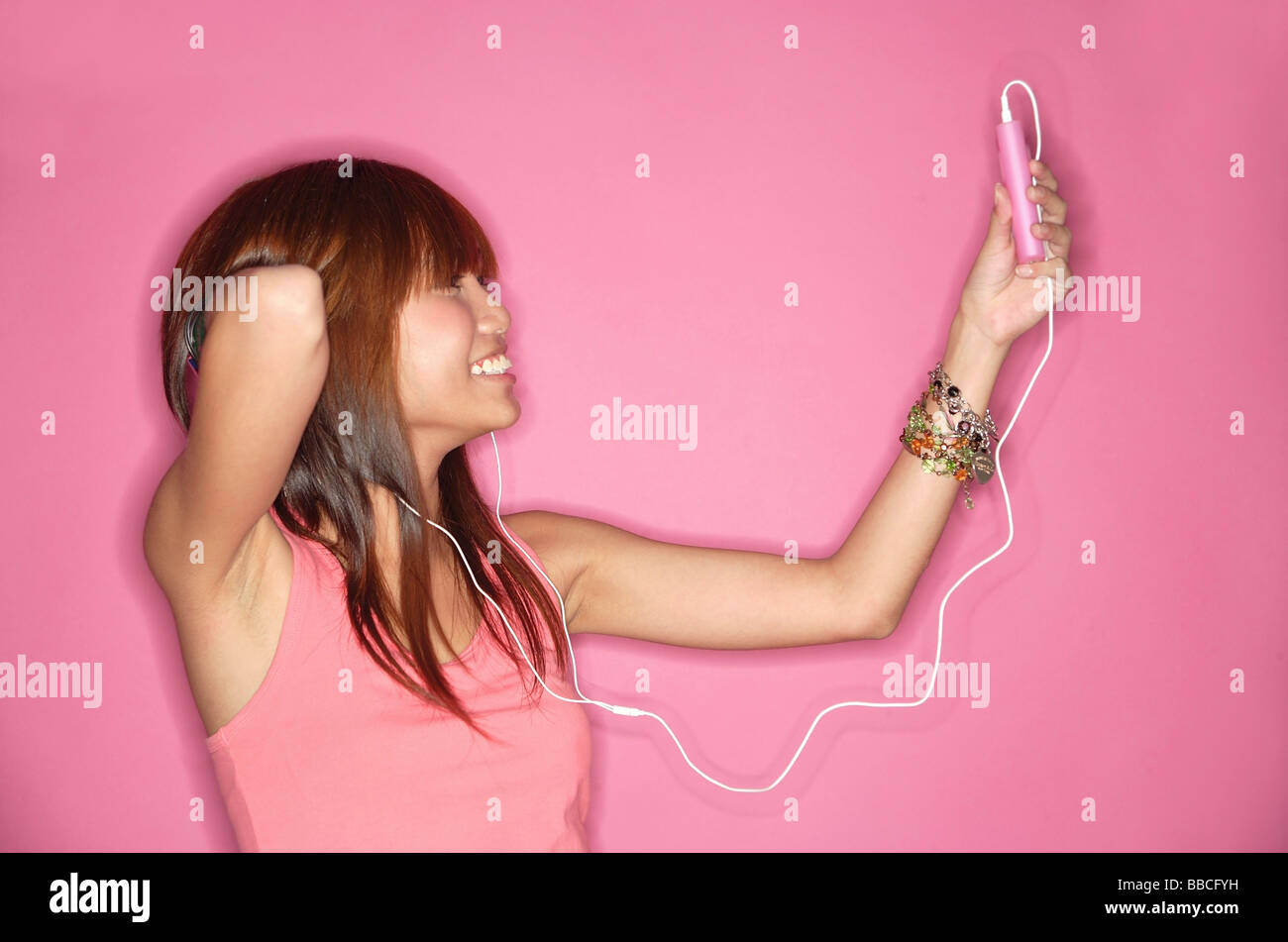 Young woman holding mp3 player, looking up, hand behind head Stock ...