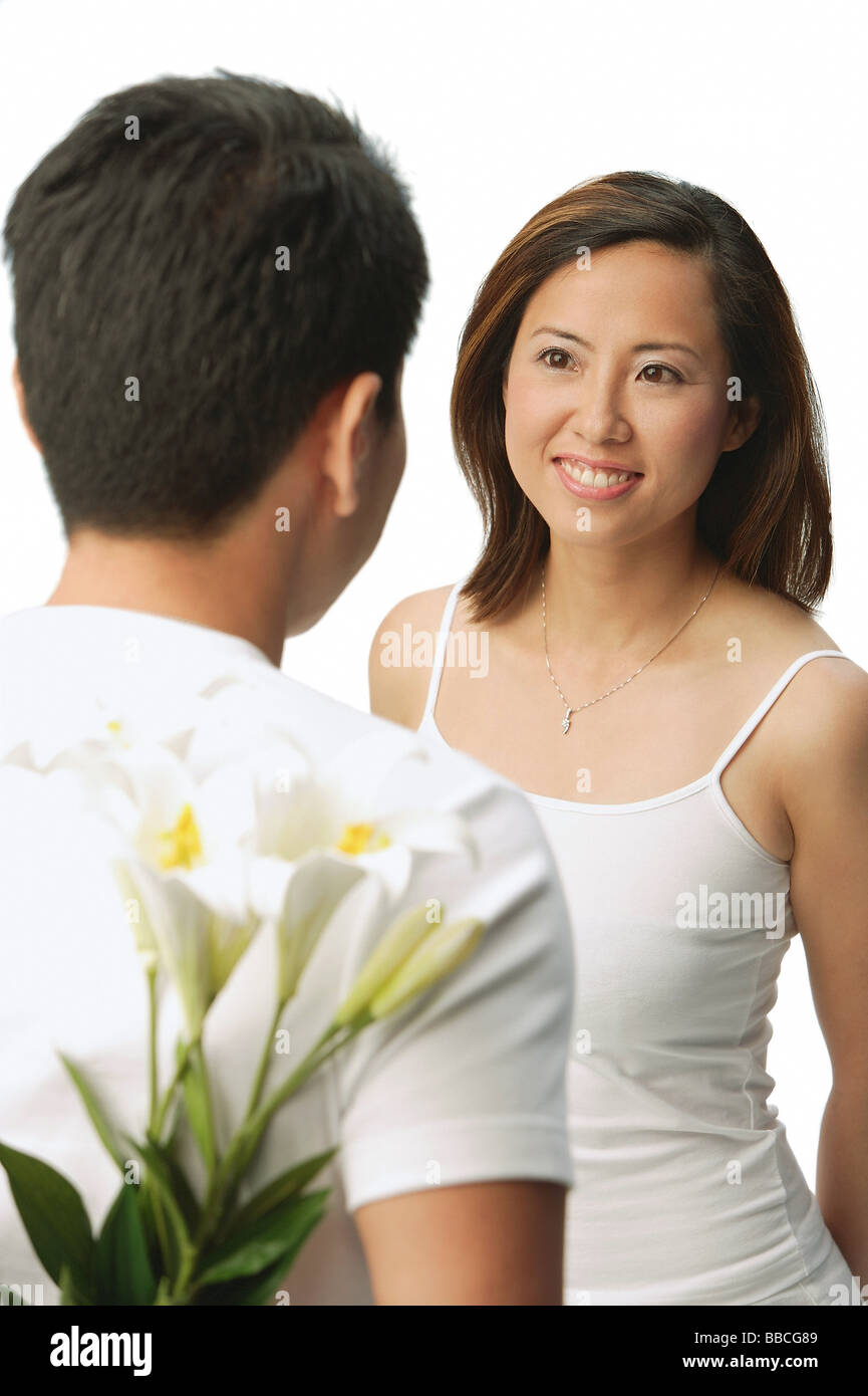 Couple facing each other, man hiding flowers behind his back Stock ...