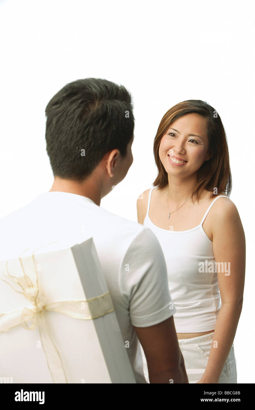 Couple facing each other, man with present behind his back, woman ...