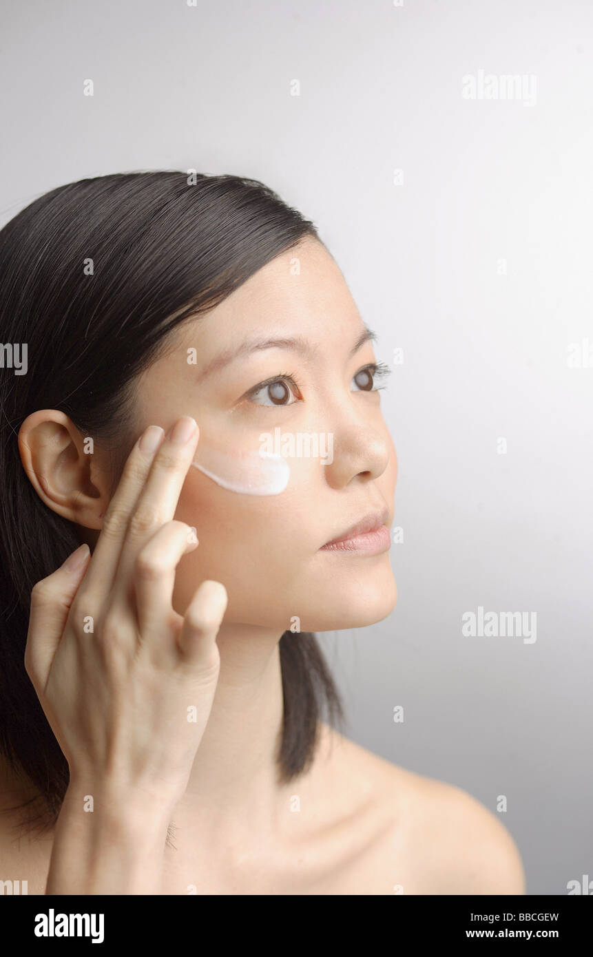 Woman applying moisturizer, side view Stock Photo - Alamy