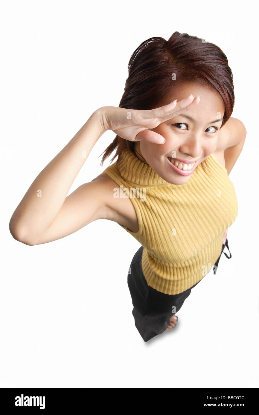 Young woman looking up at camera, hand on forehead, shielding eyes ...