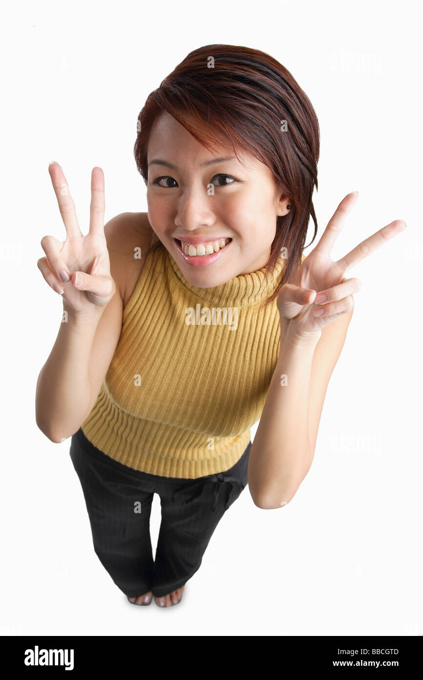 Young woman looking up at camera, making hand sign Stock Photo - Alamy