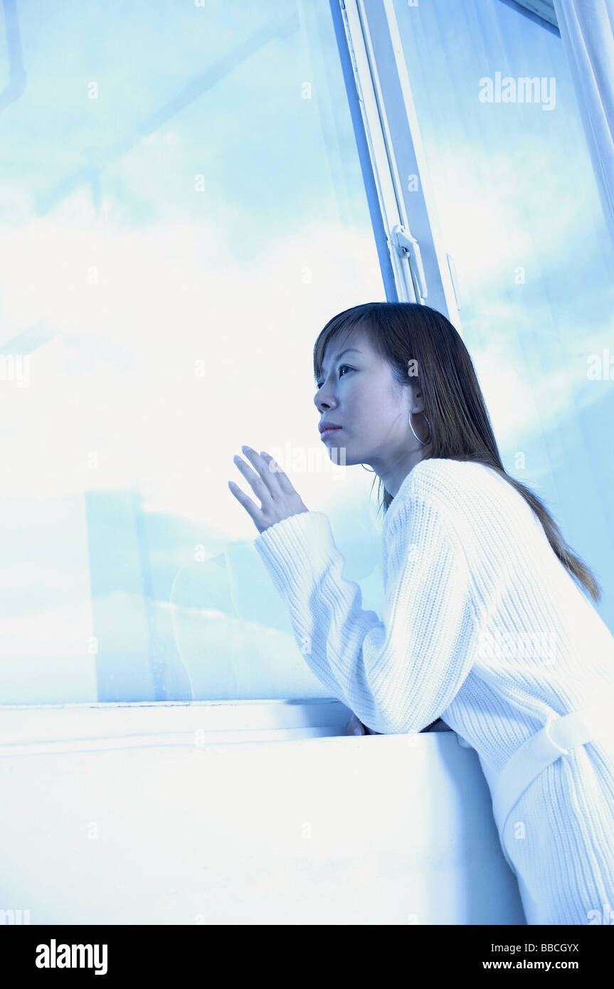 Woman leaning on ledge, looking through window Stock Photo - Alamy