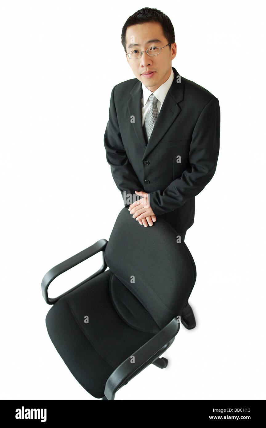 Businessman standing next to office chair, looking at camera Stock ...