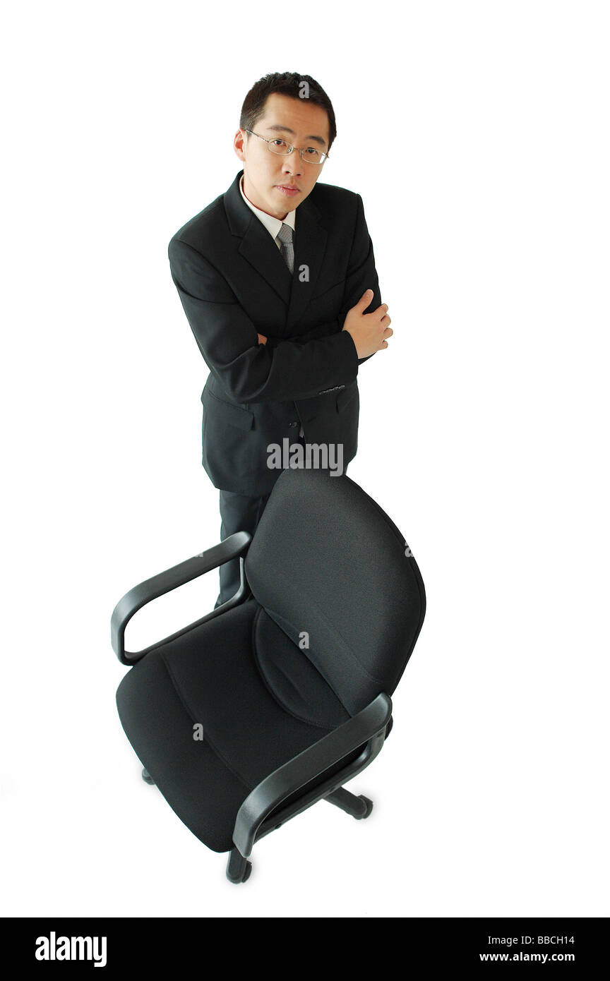 Businessman standing next to office chair, arms crossed Stock Photo - Alamy
