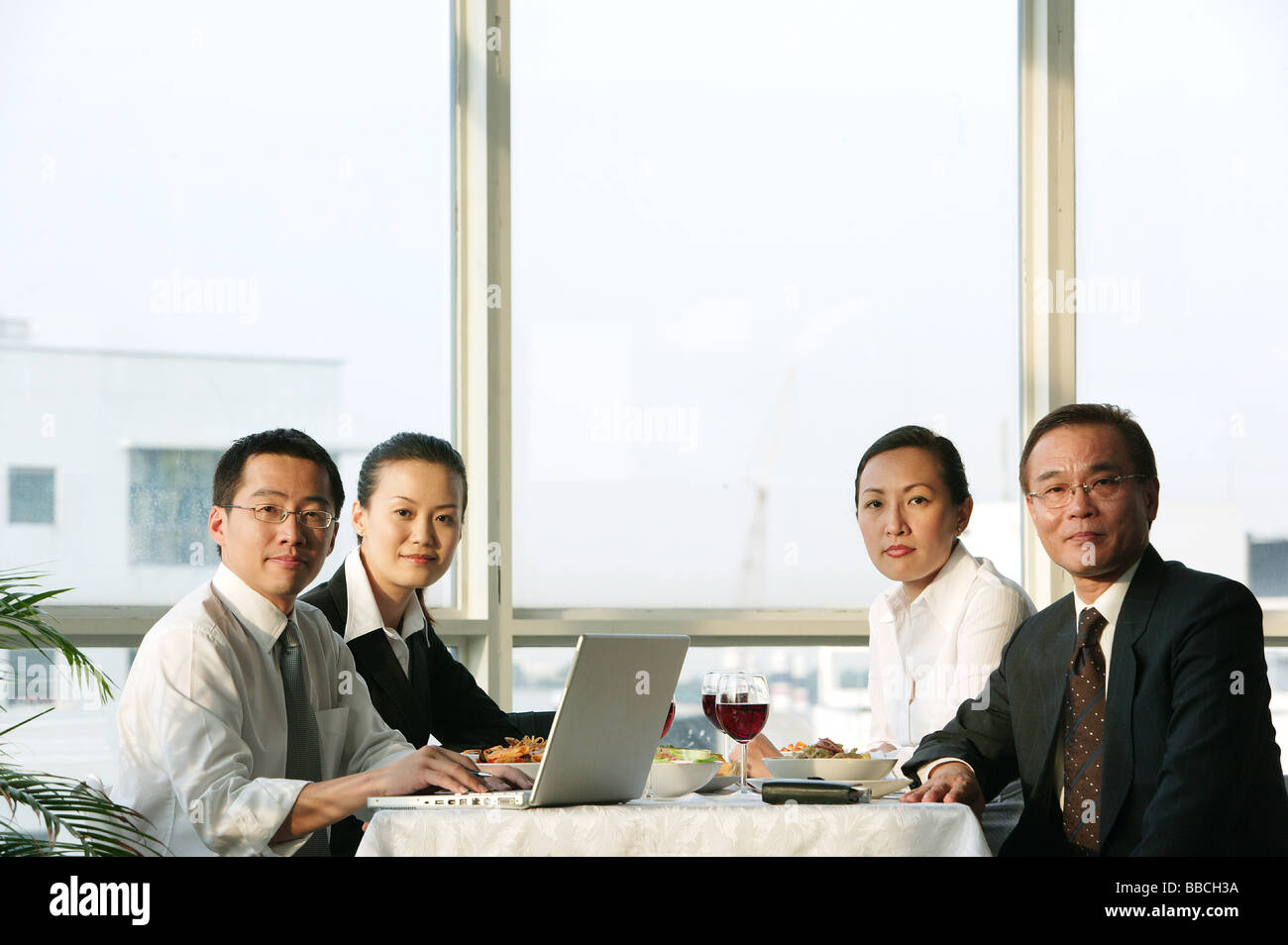 Executives sitting at lunch table, looking at camera Stock Photo - Alamy