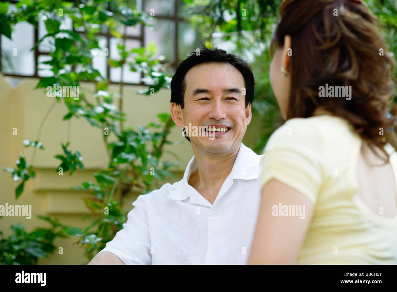 Mature couple sitting, facing each other, smiling Stock Photo - Alamy