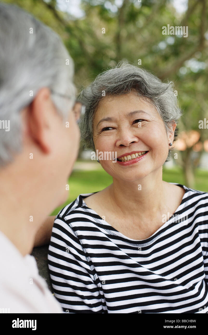 Mature couple facing each other smiling, woman wearing striped shirt ...