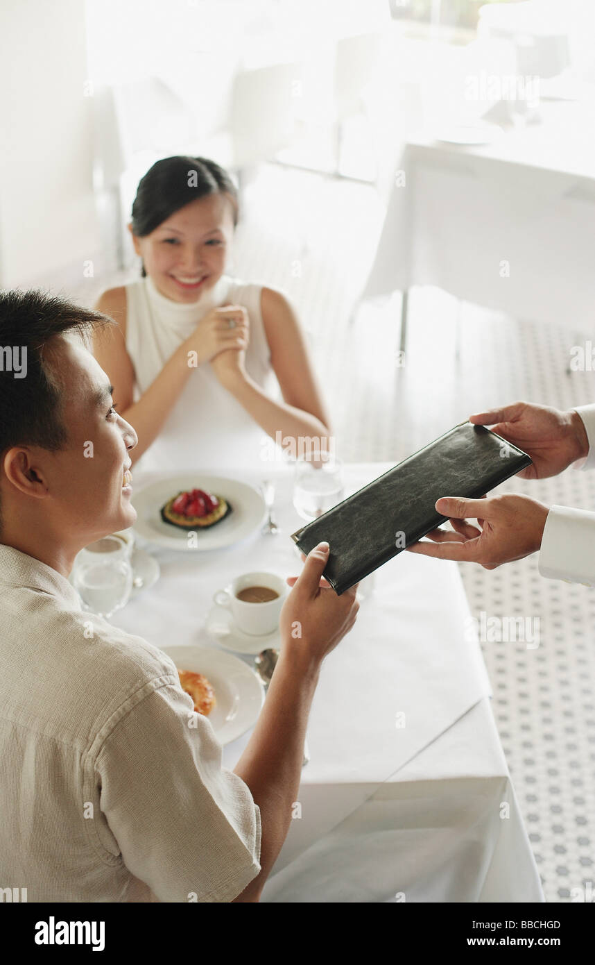 Man giving menu to waiter, woman sitting opposite him Stock Photo - Alamy