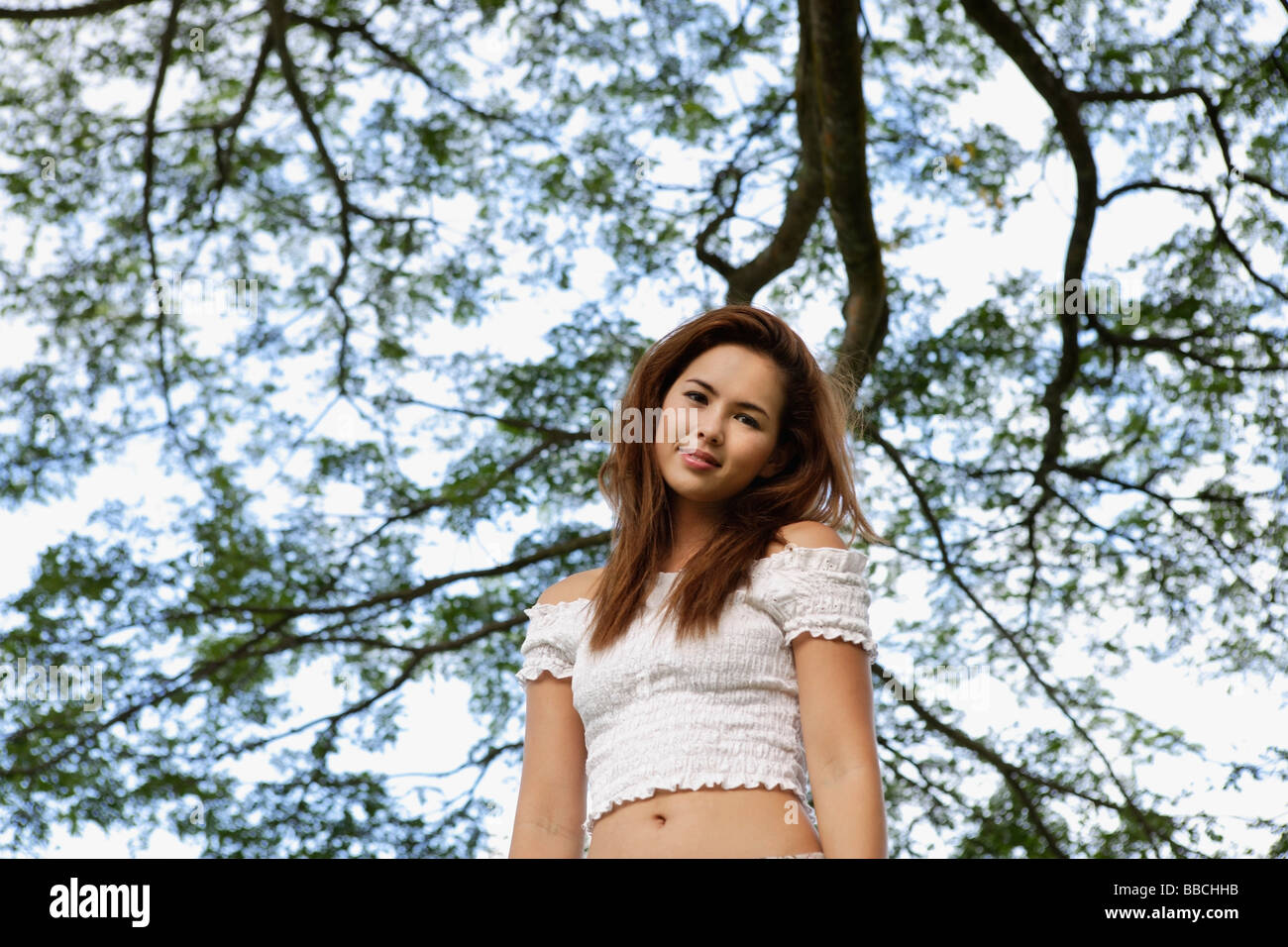 Young woman standing under tree Stock Photo - Alamy