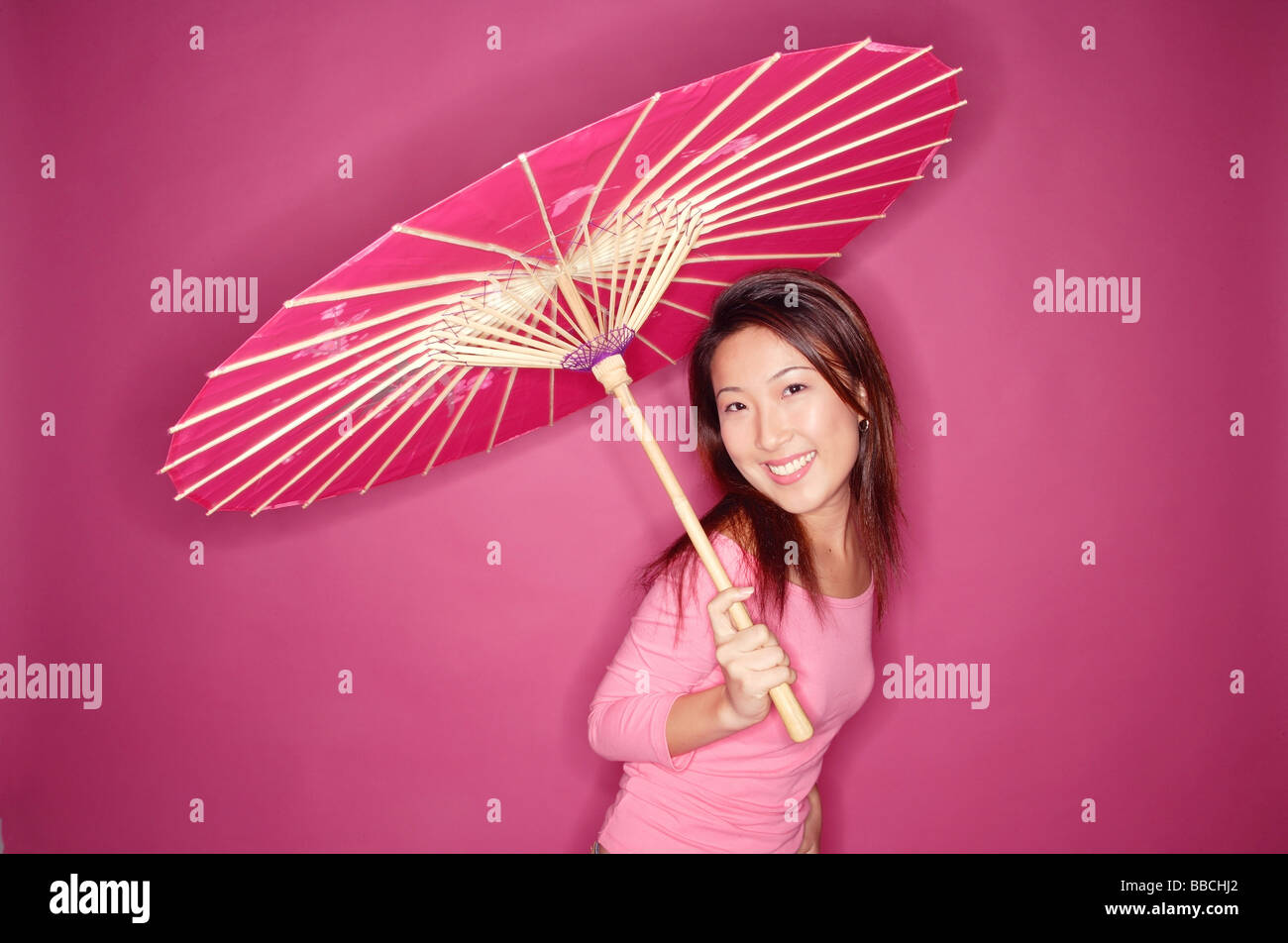Woman with umbrella, standing against pink background Stock Photo - Alamy