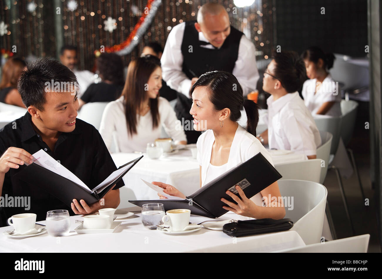 Couple in restaurant, looking at menus Stock Photo - Alamy