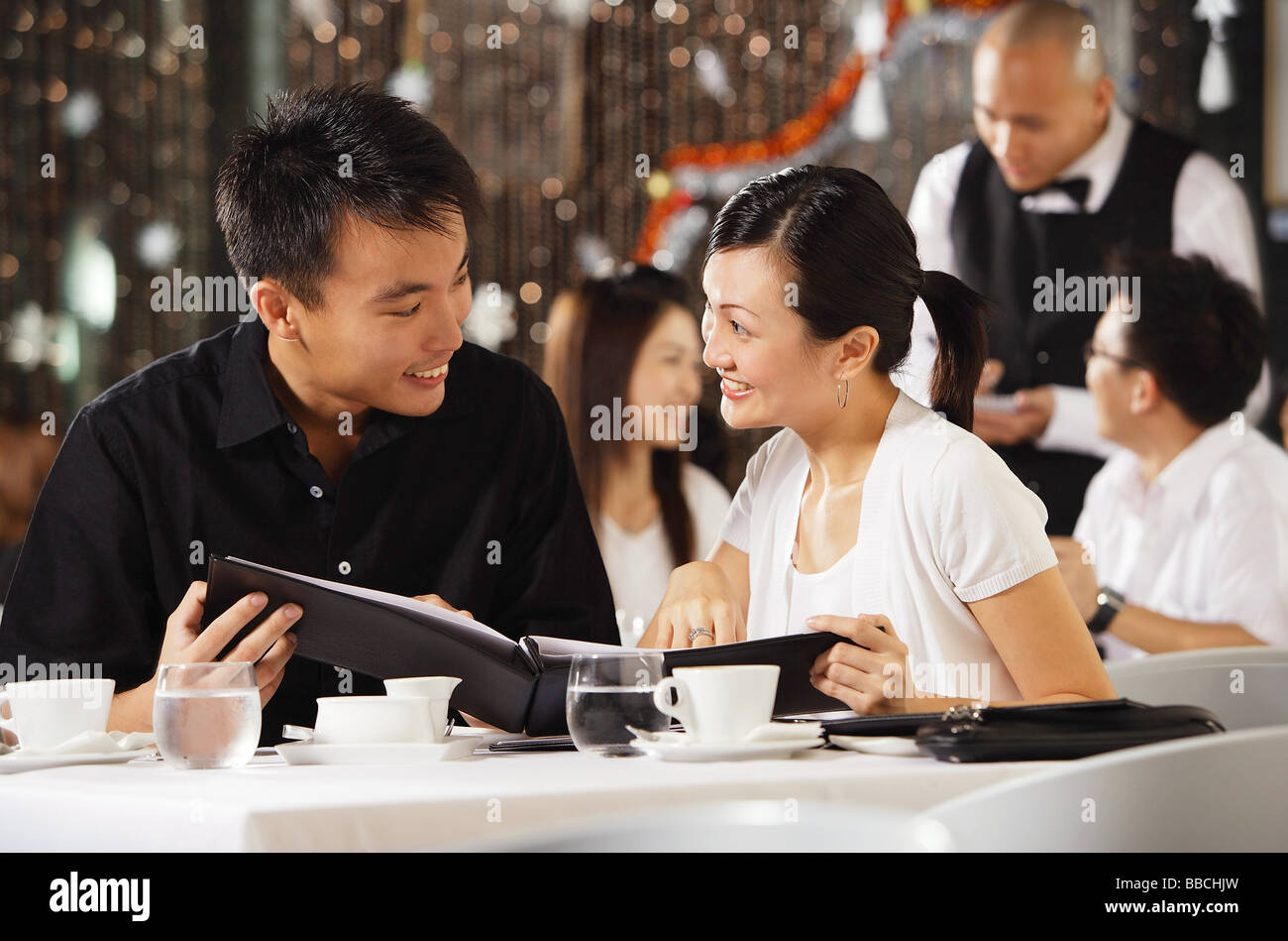 Couple in restaurant, holding menu and smiling at each other Stock ...