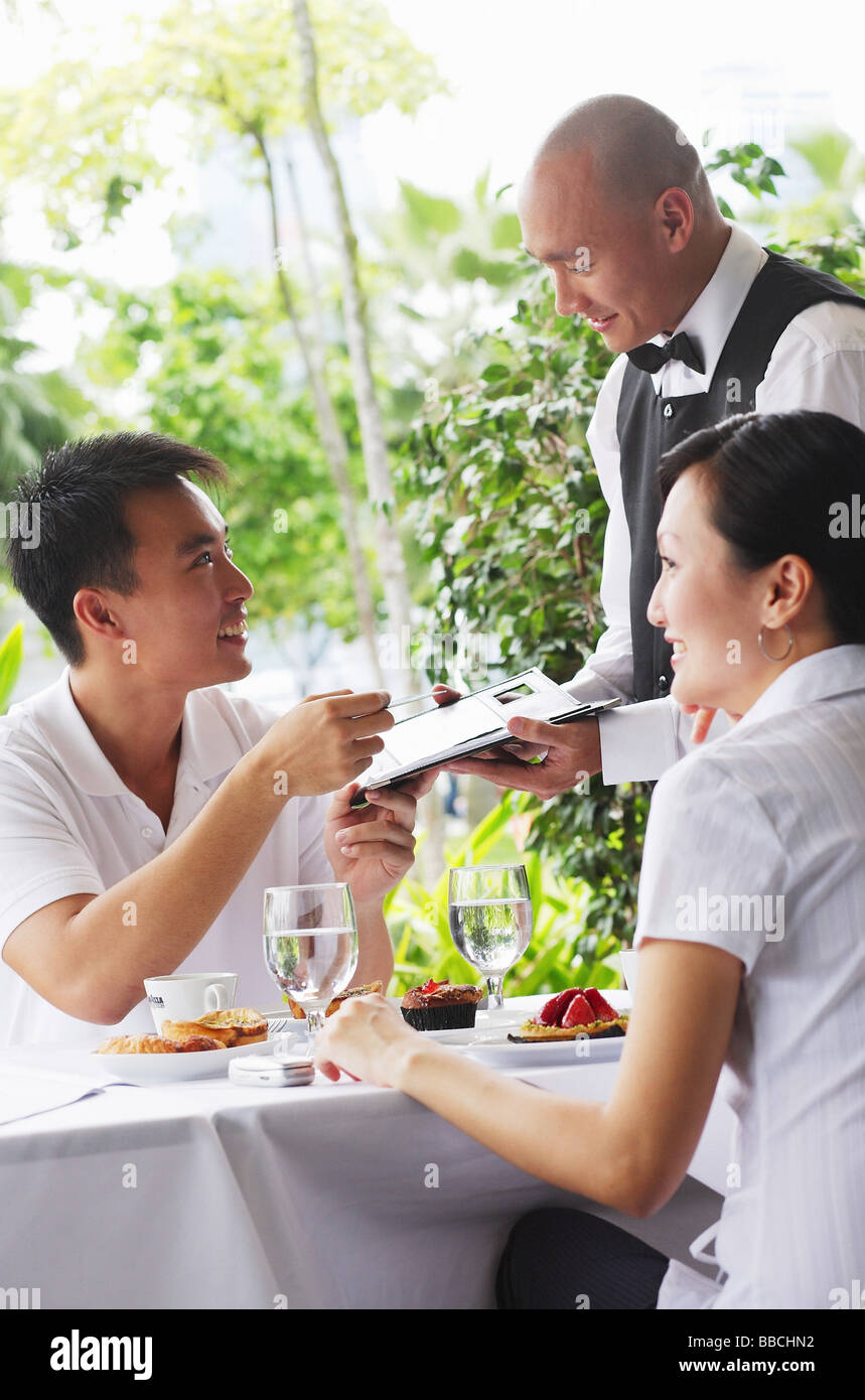 Couple in restaurant, making payment to waiter Stock Photo - Alamy