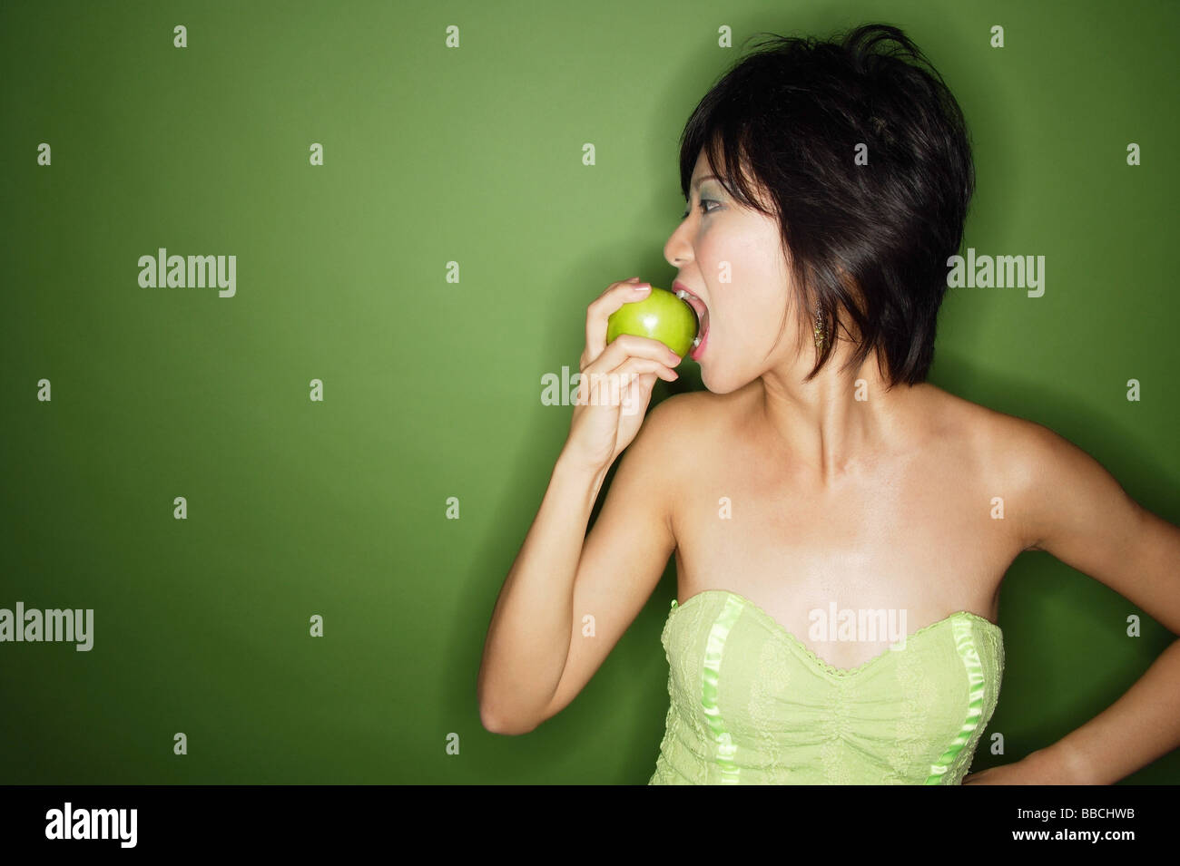 Woman biting into green apple, side view Stock Photo - Alamy