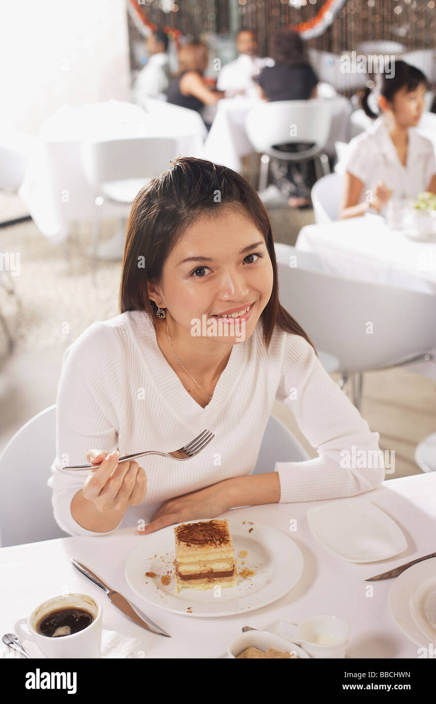 Woman at table in restaurant, dessert in front of her, smiling at ...