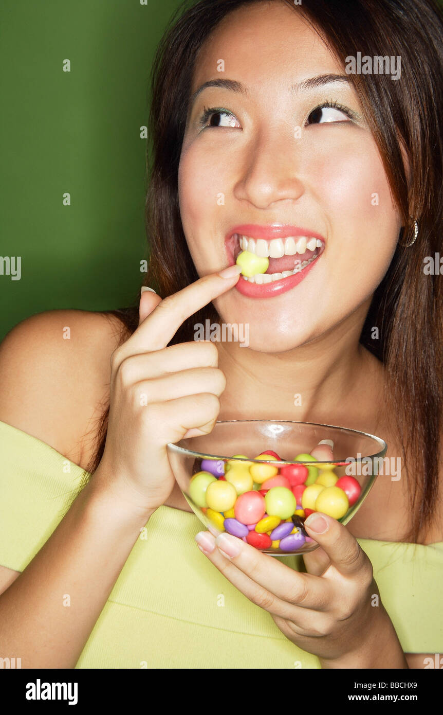 Woman with bowl of candy, putting candy into mouth Stock Photo - Alamy