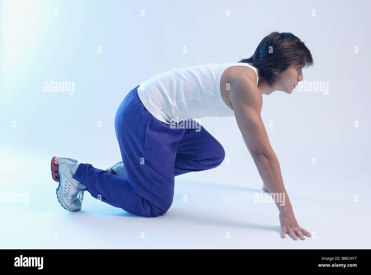 Man kneeling at starting position, looking up, side view Stock Photo ...